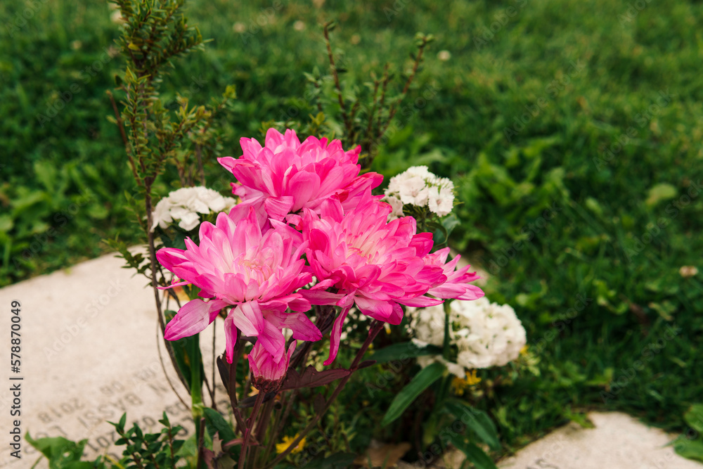 parque cementerio con pasto verde, flores de muchos colores, personas ...