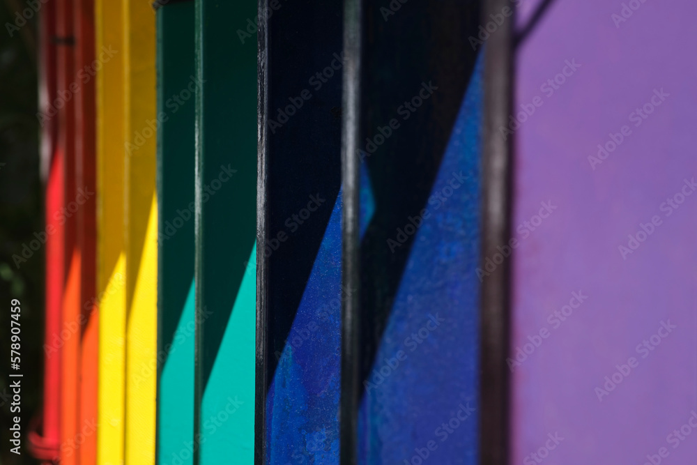 Rainbow colored fence under hard light, parallel vertical lines, and ...