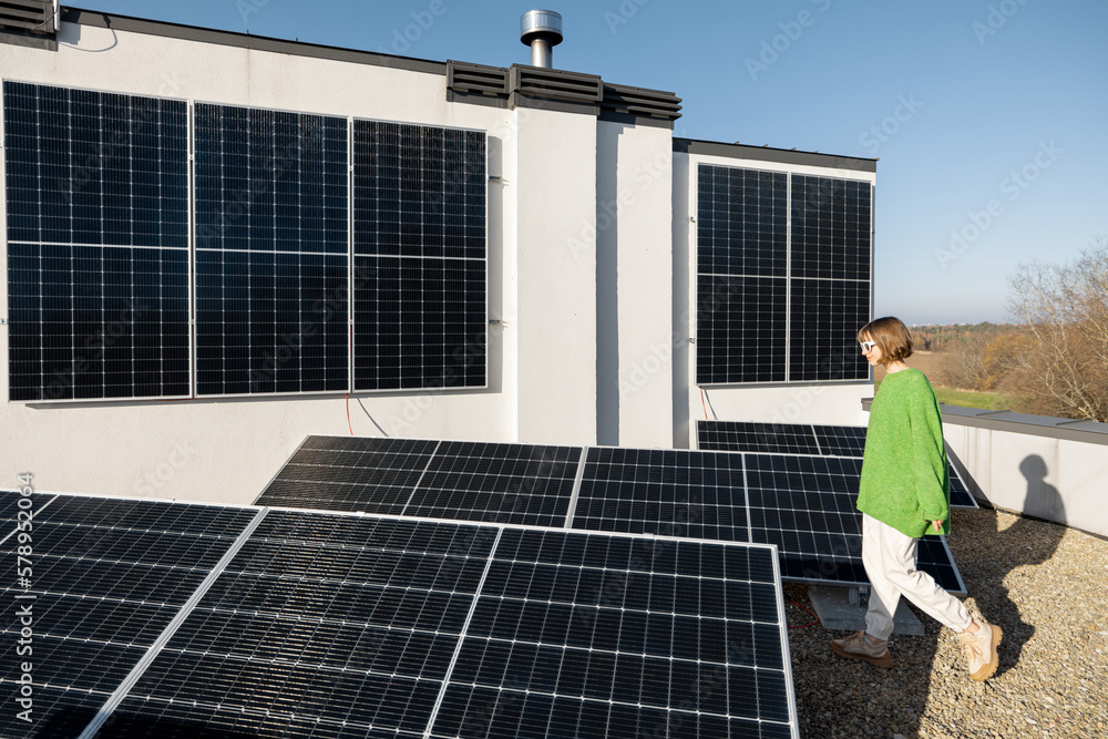 Woman on the rooftop of her house with a solar power plant installed on ...