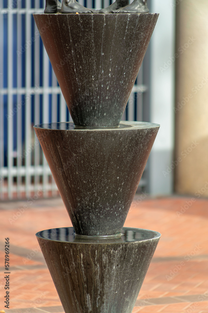 Triangular fountain design in urban area black cones and water running ...