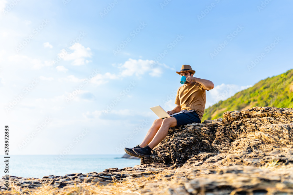 Caucasian man working outdoor on laptop computer and drinking coffee ...
