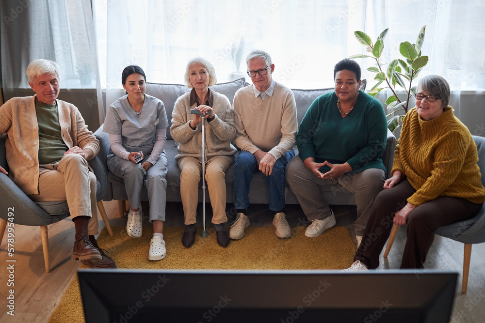 Full length view at group of elderly people watching TV in retirement ...