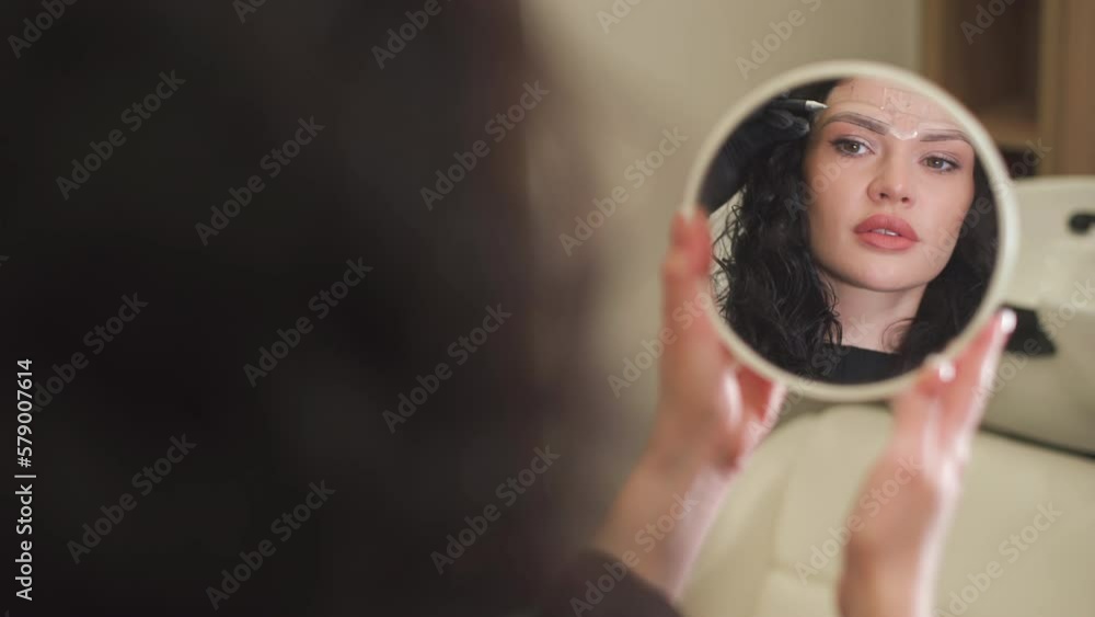 Using a mirror, a female master shows and explains what the eyebrows ...