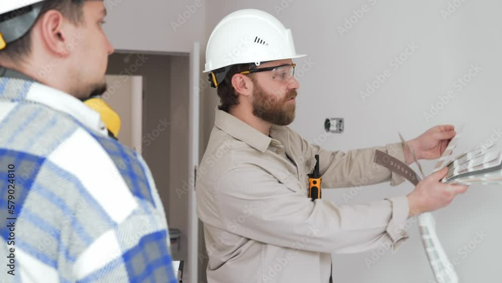 Two engineers at a construction site apply a color palette to the wall ...