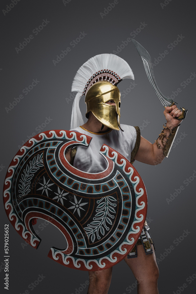 Shot of antique greek soldier with golden helmet holding rounded shield ...