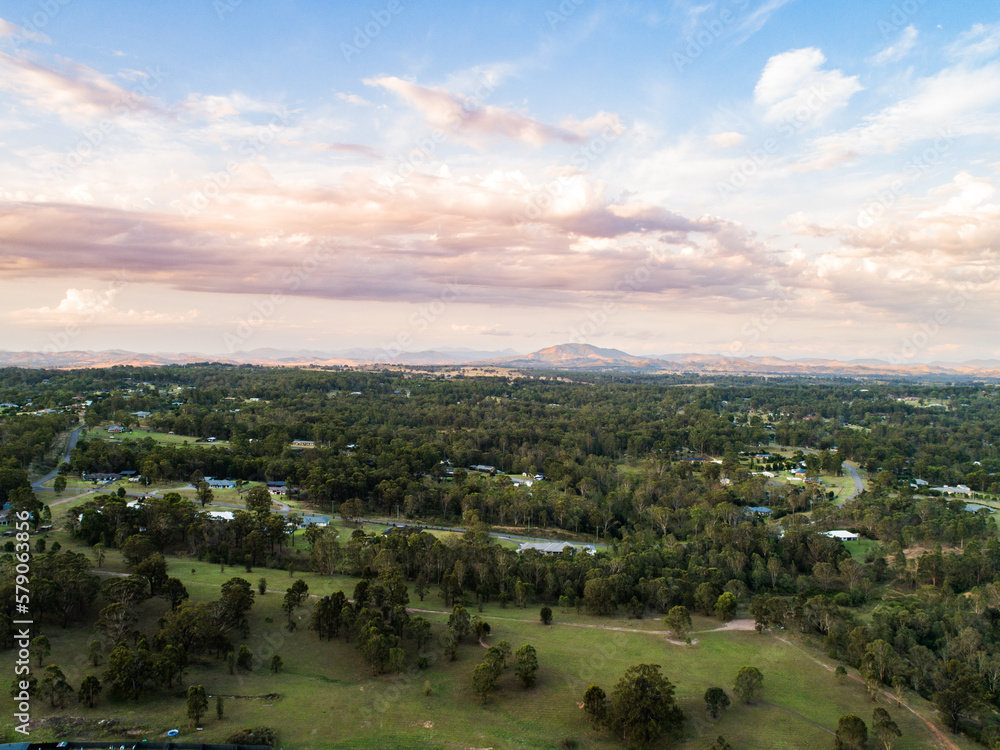 pastel cotton candy clouds and sunlit hills on horizon with dull park ...