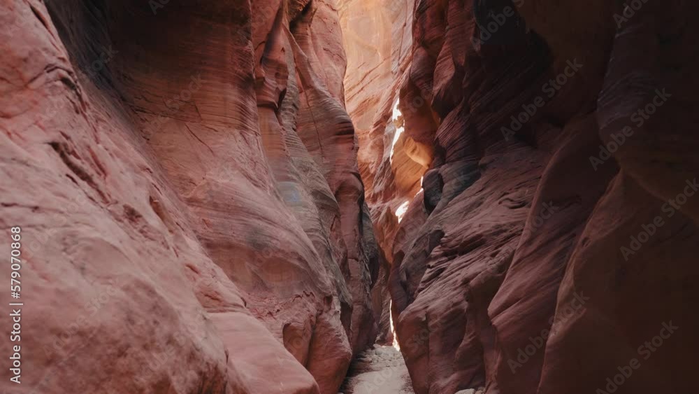 Moving forward in narrow deep slot canyon with smooth red sandstone ...