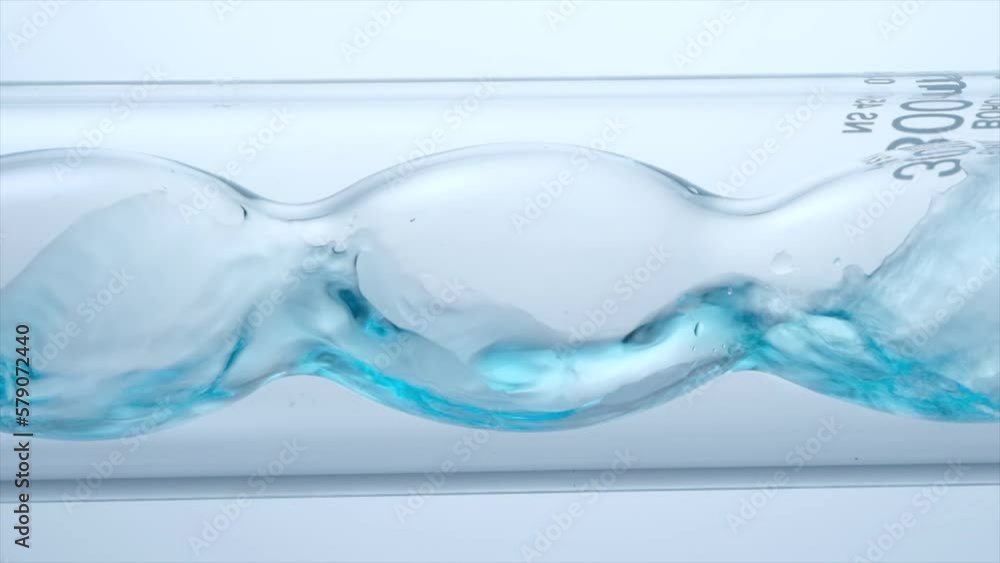 Blue solution flows fast through the test tube with close-up view ...