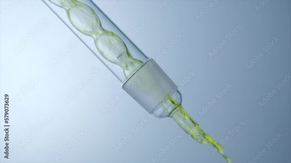 Colored fluid flowing through a glass test tube. Close up. Laboratory ...