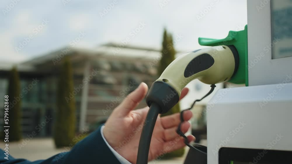 Hand pulling in cable from EV car charger or electric vehicle station ...