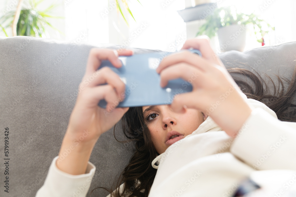 Teenage girl watching her mobile phone at home on the sofa Stock Photo ...