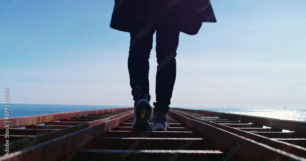 Vidéo Stock Man in dark coat walks to edge of pier metal structure at ...