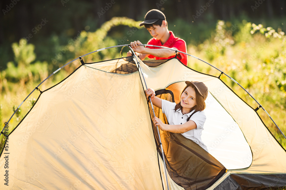 Family recreation in nature in summer. Two young teenage children are ...