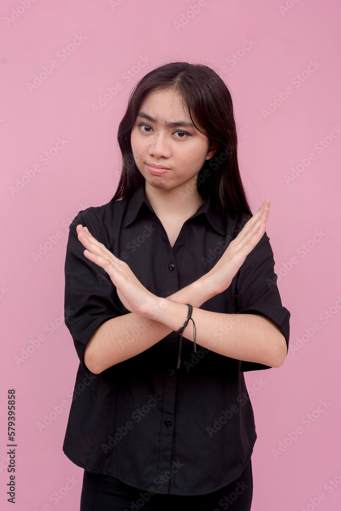 An opinionated young asian woman makes a x sign with both hands as a ...