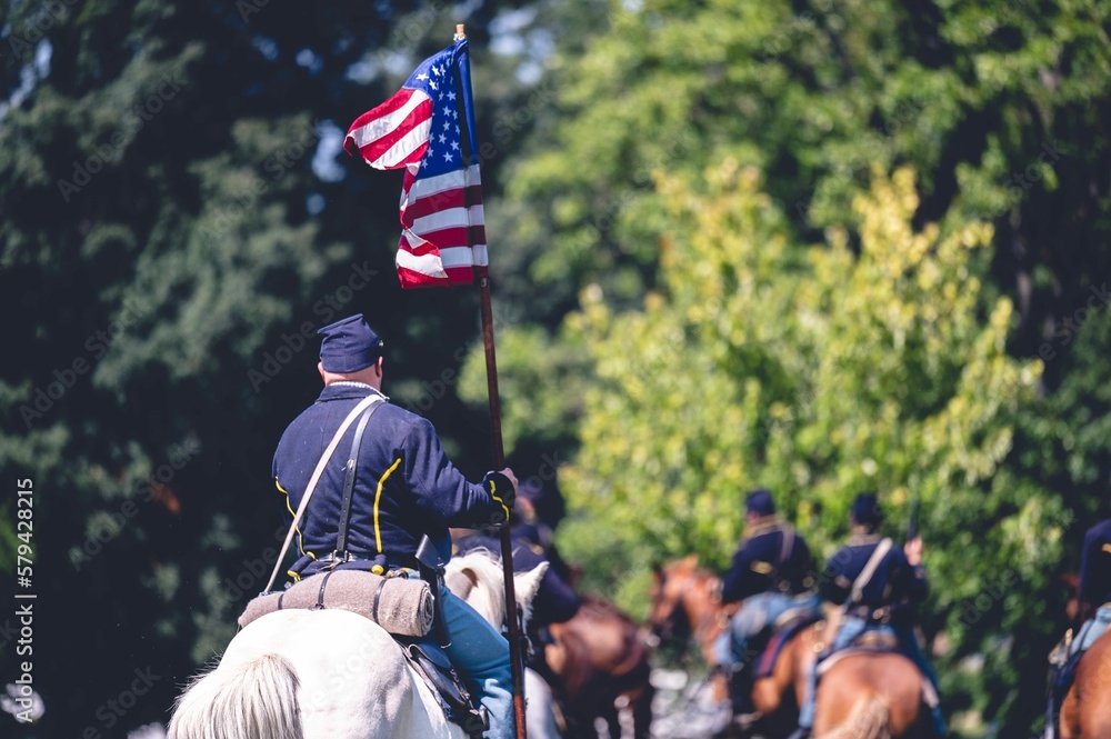Soldier riding a horse and raises the flag of America during military ...