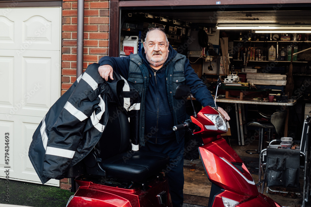 Portrait of elderly man standing near mobility scooter on the ...
