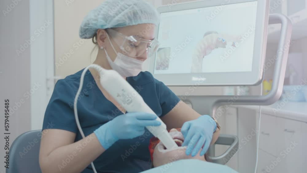 Doctor scans the patient's teeth in the clinic. The dentist holds in ...