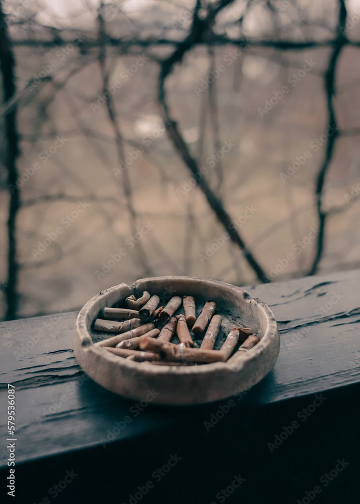 A clay ashtray with butts on a wooden terrace beam. Smoking on the ...