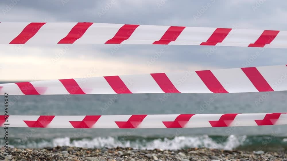 Red white warning tape barrier ribbon swinging in the wind across ...