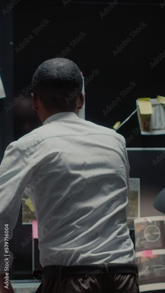 Vertical video: Professional police officer hanging clues on wall map ...