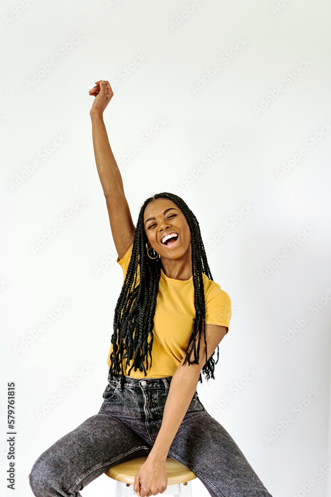 Smiling black woman sitting on chair against white wall Stock Photo ...