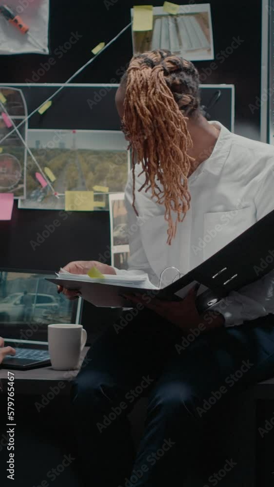 Vertical video: Two police officers looking at detective evidence map ...