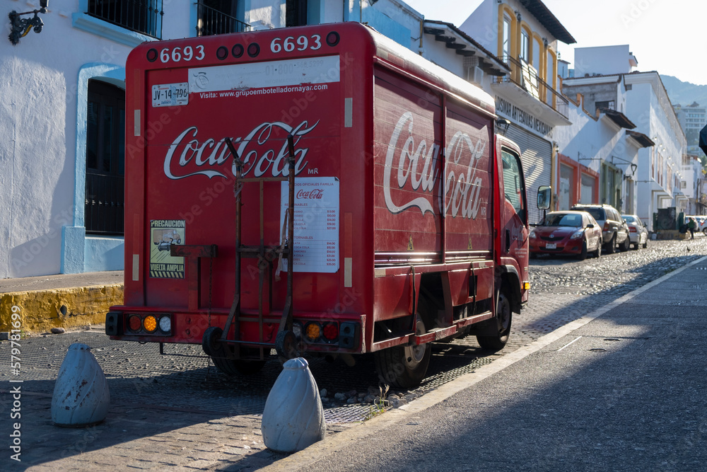Bright red Coca Cola delivery truck on a street delivering products to ...