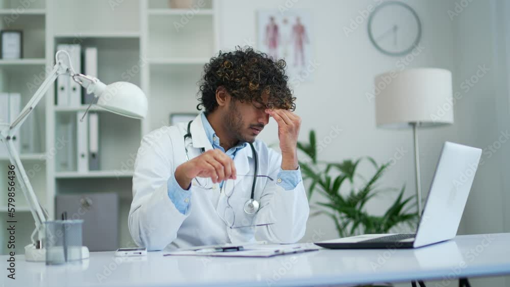 Tired doctor at workplace in office of the clinic work at computer ...