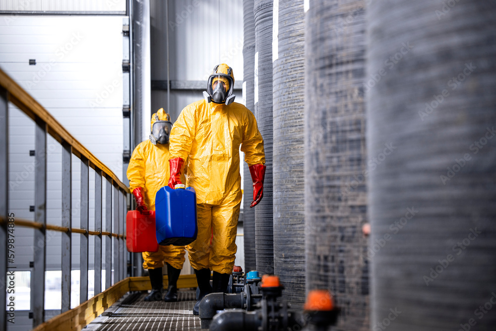 Fully protected workers in yellow suit, gas masks and gloves handling ...