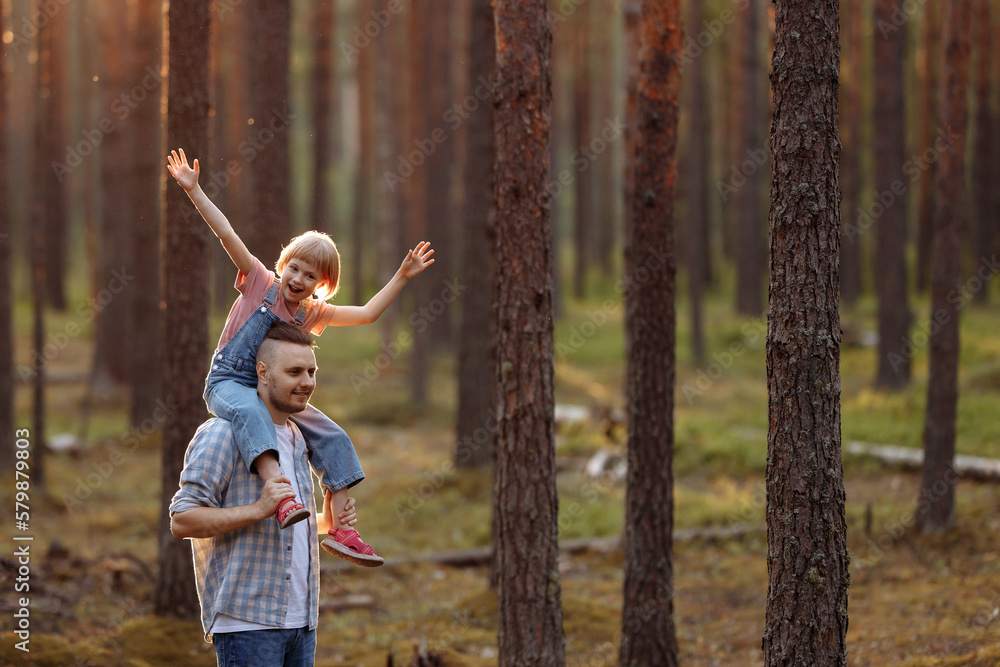 Dad holds a little daughter in his arms, they laugh merrily walking ...