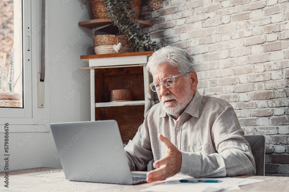 Annoyed worried aged man pensioner sit by laptop unable to make utility ...