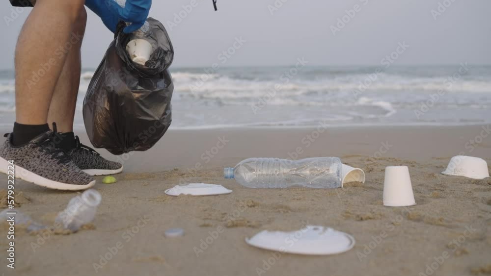 Close up. Volunteers walk and pick up garbage on the beach. Cleaner ... Close up. Volunteers walk and pick up garbage on the beach. Cleaner ...
