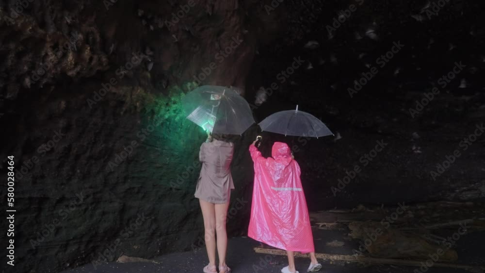 Two female persons exploring a dark bat cave. Anime style footage of ...