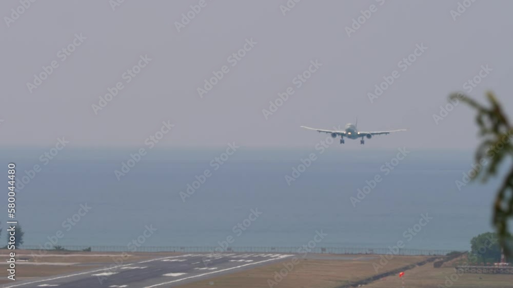 Jet passenger plane descending on landing, background of the sea. An ...