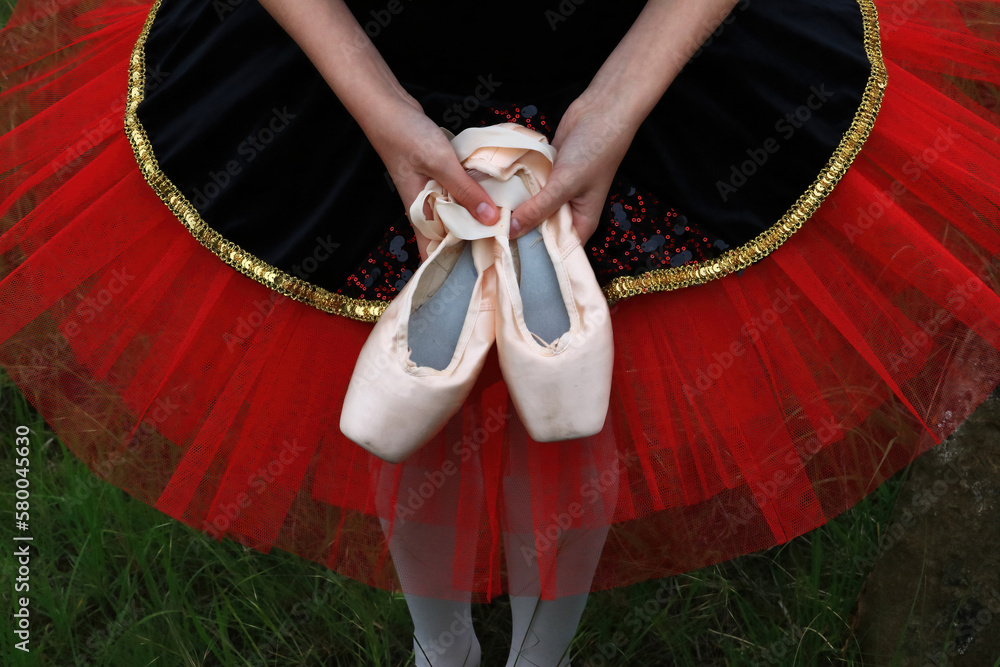 Looking down from above at the waist of a ballerina wearing a red and ...