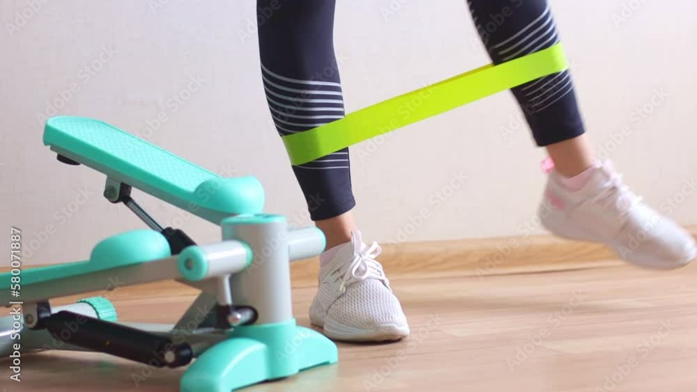 Exercises on the lower body. Woman trains with an elastic band at home ...