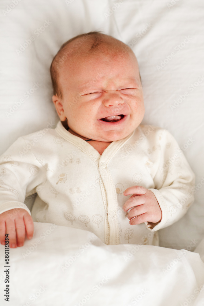 Crying tired infant baby try to sleep in bed with sick face skin top ...