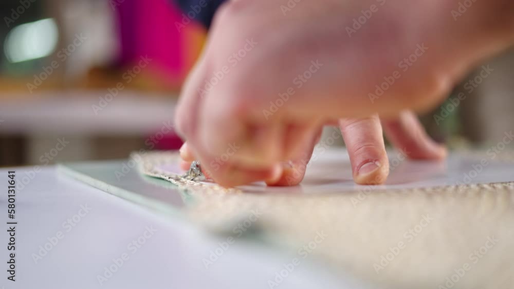 Close-up man's hand cutting out of leather piece with a special knife ...