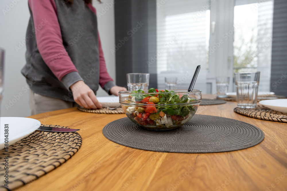 Woman with daughter setting the table for lunch time in her domestic ...