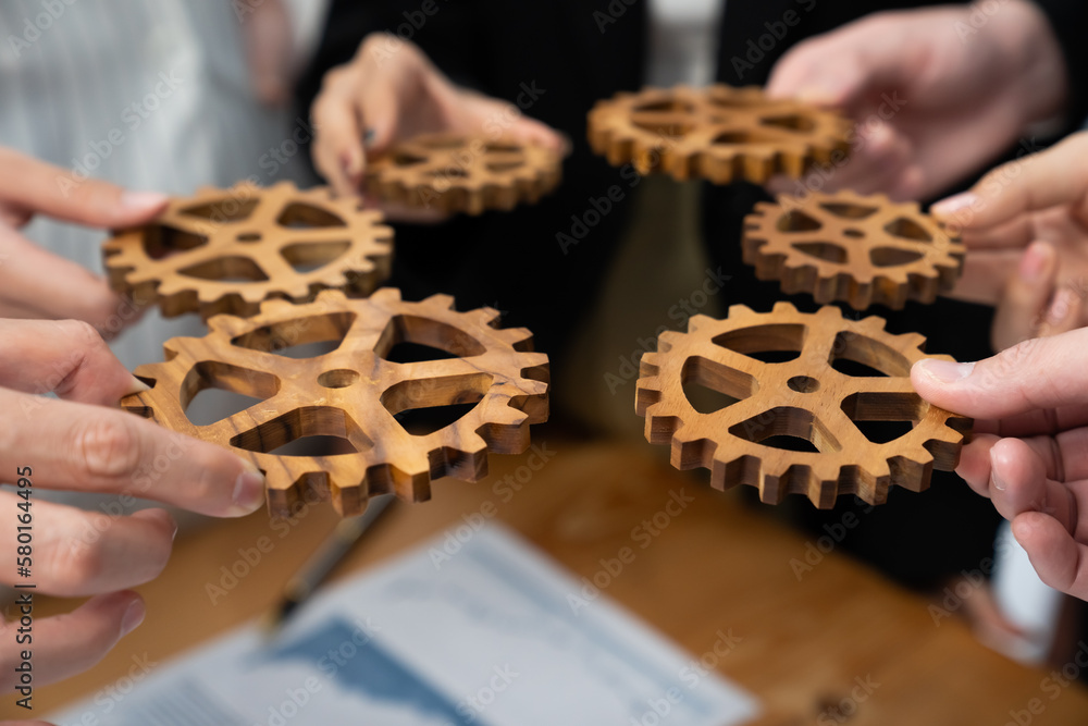 Closeup hand holding wooden gear by businesspeople wearing suit for ...