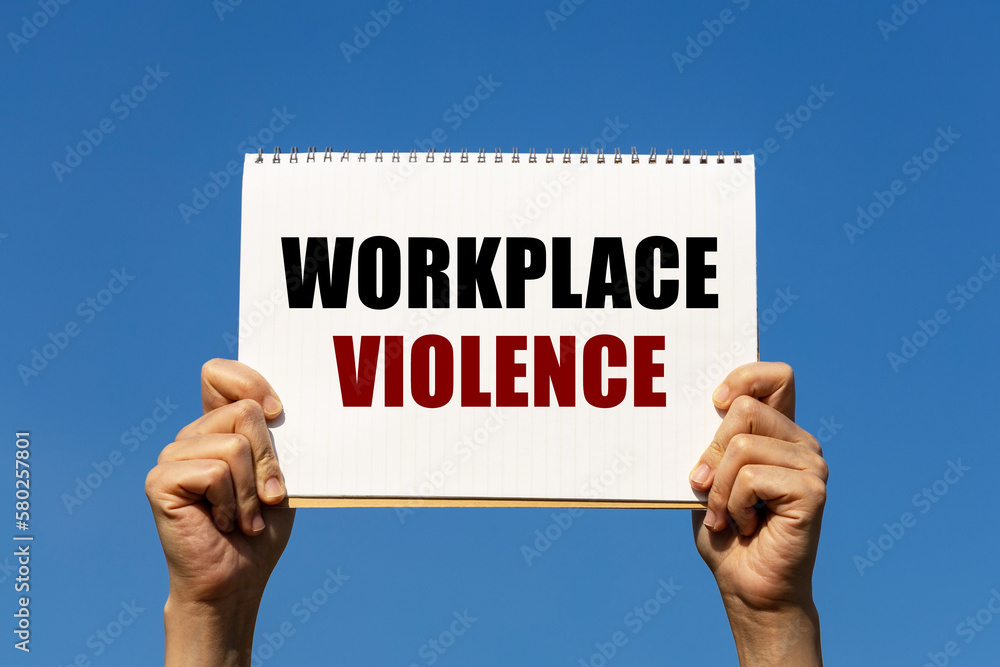 Workplace violence text on notebook paper held by 2 hands with isolated ...