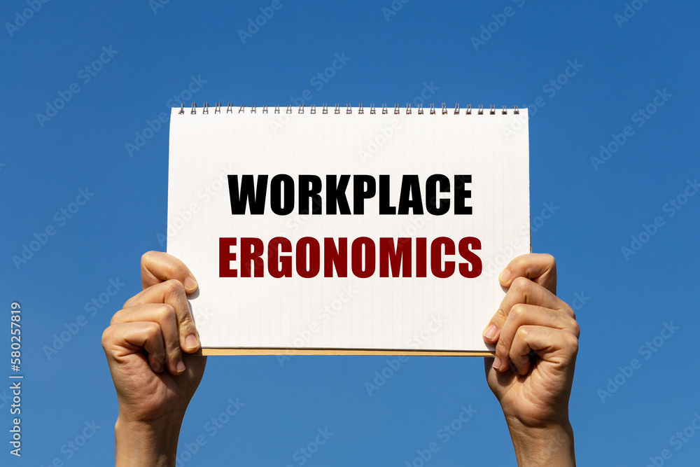 Workplace ergonomics text on notebook paper held by 2 hands with ...