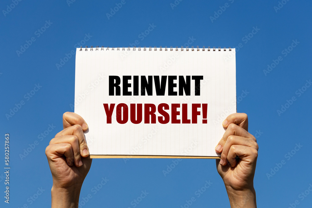Reinvent yourself text on notebook paper held by 2 hands with isolated ...