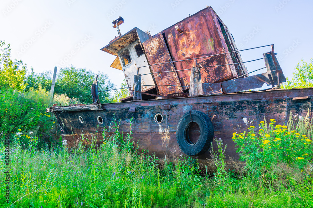 Old rusty ships lie on the riverbank. The river bank and rusting ships ...