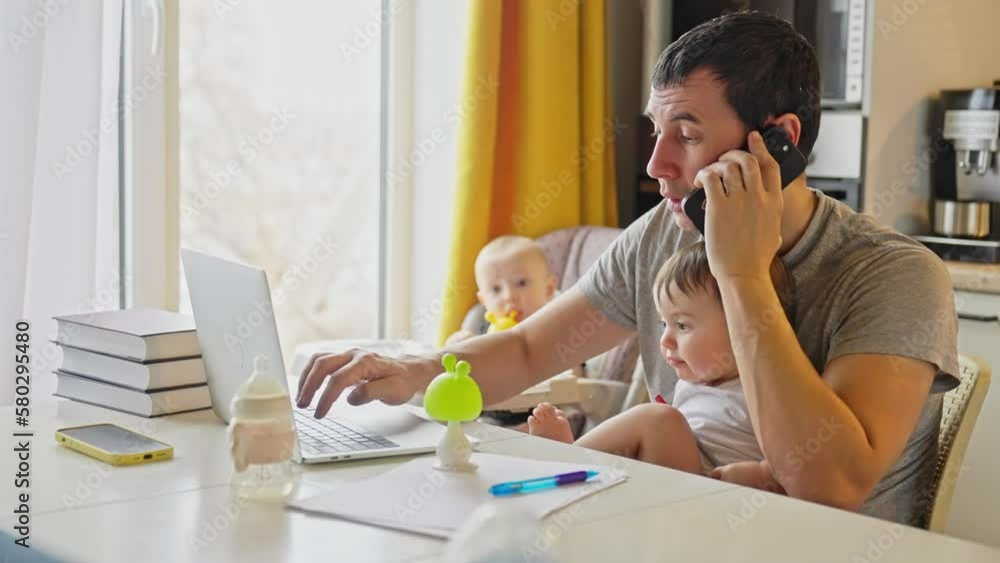 father working from home remotely with baby daughter in his arms ...