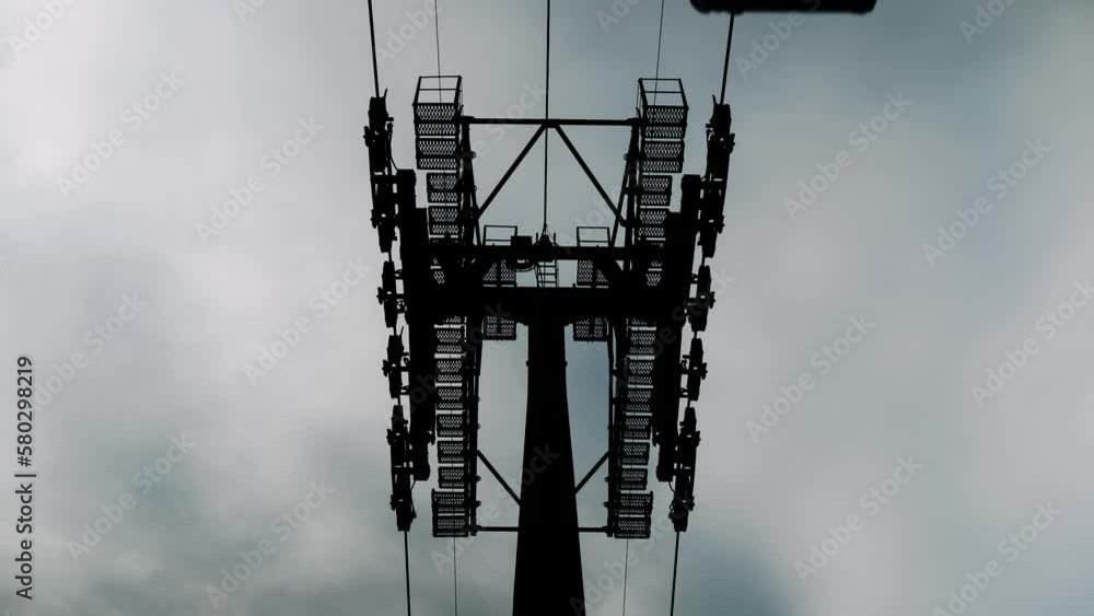 Ropeway, cable car cabins silhouettes are moving against gray sky in ...