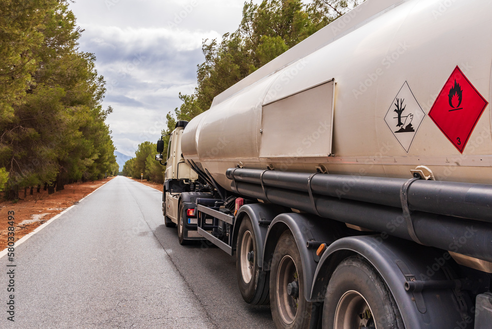 Fuel tanker truck circulating on a narrow and straight road through a ...