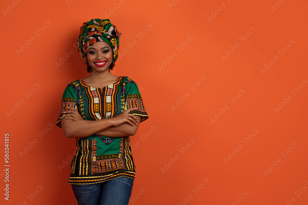 Positive black woman in traditional african costume posing on orange ...
