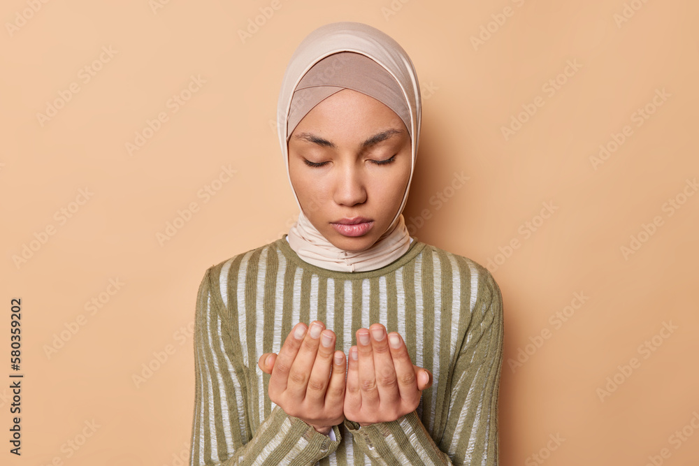Religious Muslim woman keeps eyes closed gestures stands in praying ...