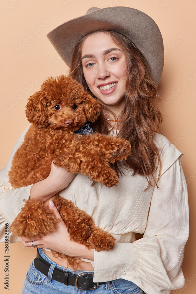 Foto de Happy woman poses with adorable poodle puppy smiles broadly ...